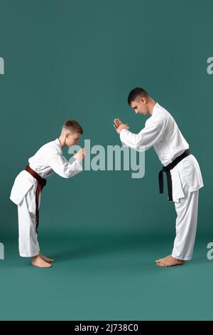 Boy and sensei performing ritual bow before practicing karate on yellow ...