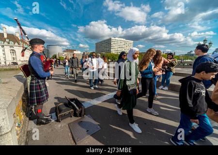 A piper plays on the London bridge, in front of the London eye Stock ...