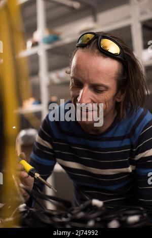 Industrial worker man soldering cables of manufacturing equipment in a ...