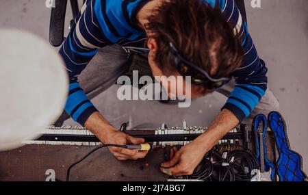 Industrial worker man soldering cables of manufacturing equipment in a ...