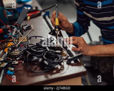 Industrial worker man soldering cables of manufacturing equipment in a ...