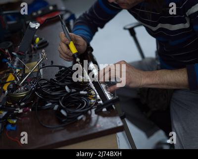 Industrial worker man soldering cables of manufacturing equipment in a ...