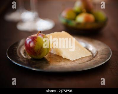 Wedge of aged cheese on rustic wooden board beside green olives in ...