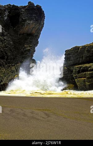 Splashing waves. Black rocky volcanic beach with black lava stones ...