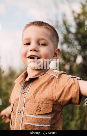 A little boy stands in nature and smiles Stock Photo - Alamy