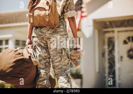 Rearview of a patriotic female soldier standing in front of her home ...