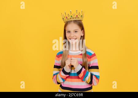 Teen child in queen crown isolated on yellow background. Princess girl ...