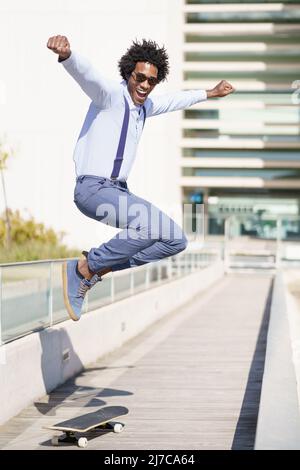 Full body of male skater in casual clothes performing extreme trick on ...