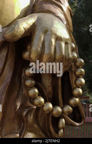 Details of laughing Buddha statue showing the left-hand holding prayer ...