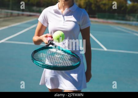 Midsection of young female caucasian player with racket and ball at ...