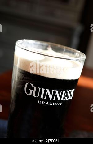 A branded glass of Guinness stout beer with creamy froth head at the ...