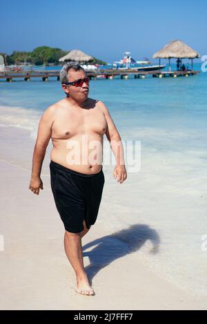 Funny fat man on the ocean eating fruits Stock Photo - Alamy