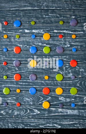 A set of colorful glass buttons for clothes on a dark wooden background ...