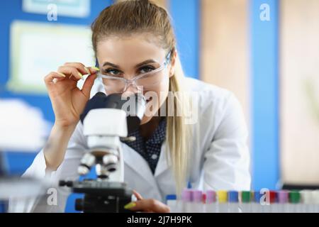 Clever laboratory lady in medical gown investigate sample under ...