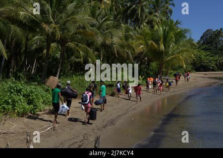Local people carrying luggages belong to tourists, walking along the ...