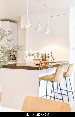 Comfortable chairs placed at counter in modern spacious open plan ...