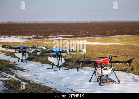 Many agrodrones are on the green field. The snow has not melted yet ...