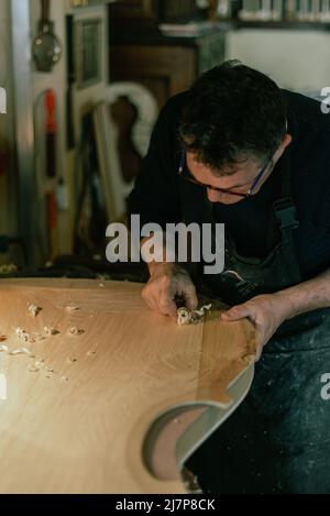 Luthier making double bass musical instrument at workshop Stock Photo ...