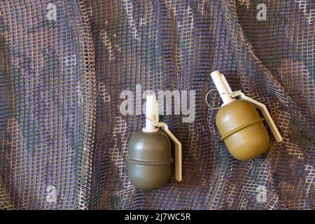 Two grenades lie on a camouflage background. The concept of military ...