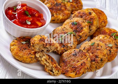 cauliflower patties on white plate with tomato sauce on white textured ...