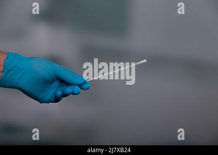 Close-up of doctor's hand handling a smear test or swab test in a ...