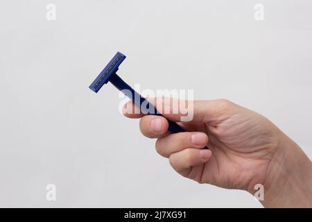 Hand holding a razor blade on a white background Stock Photo - Alamy