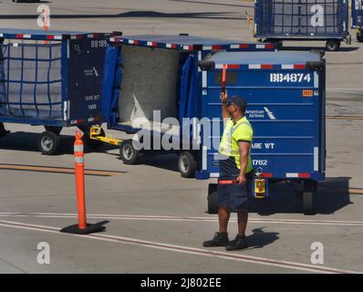 A ground crew member helps direct an American Airlines plane to its ...
