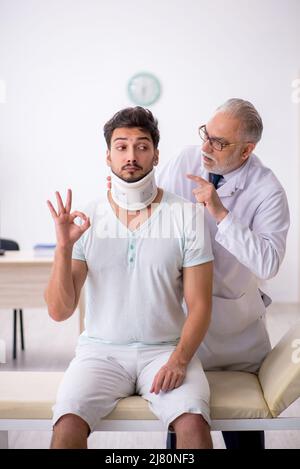 Young neck injured patient visiting old doctor Stock Photo - Alamy