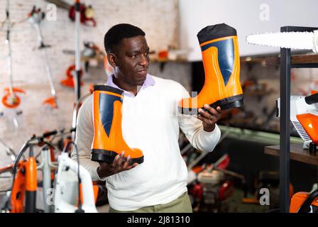 Male shopper chooses rubber boots at garden tool store Stock Photo - Alamy