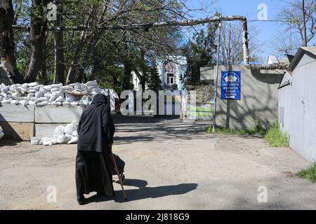 An elderly nun in a black cassock with a stick and a wheelbarrow in her ...