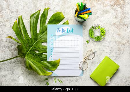 Blank to do list, stationery, eyeglasses and palm leaf on light ...