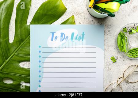Blank to do list, stationery, eyeglasses and palm leaf on light ...