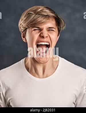 Furious, enraged young man over gray background Stock Photo - Alamy