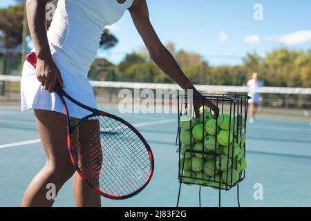 Midsection of african american female player holding ball on racket at ...