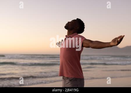 Side view of african american young man with eyes closed at beach ...