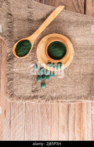 Green tablets in the wooden spoon, spirulina or chlorella food ...