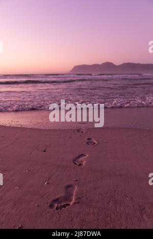 Scenic view of the footprints on the sandy beach lit by sunlight at the ...