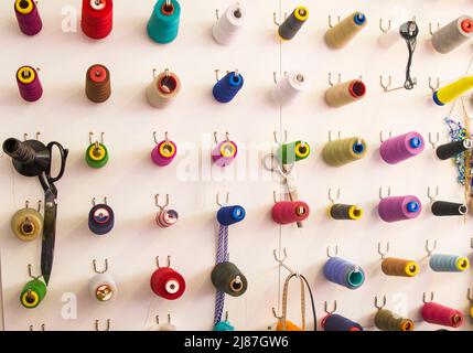 Multicolored coils and scissors on the wall. Workplace seamstresses ...