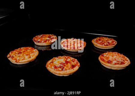 Six baked homemade mini pizzas in electric oven at home, black ...