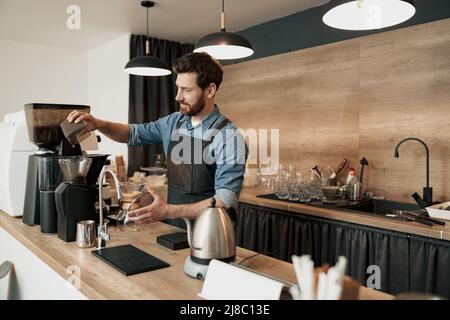 Barista grinds coffee beans before making coffee Stock Photo - Alamy