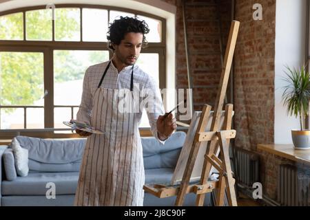 Young hispanic man artist drawing with unhappy expression at art studio ...