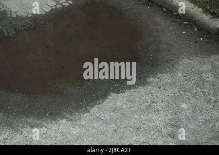 a deep puddle in the cracked asphalt Stock Photo - Alamy