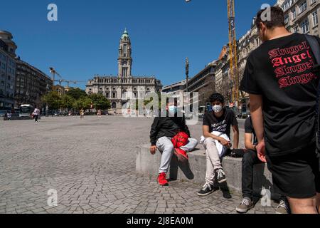 People wearing protective masks sit near the municipal park in Porto ...
