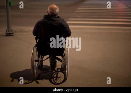 Wheelchair accessible at night. Man in wheelchair for disabled on road ...