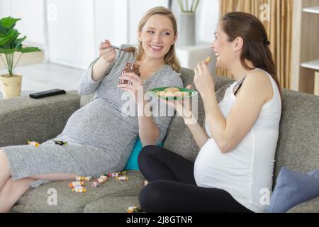 two pregnant women eating chocolate Stock Photo - Alamy