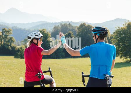 Two road cyclists silhouettes celebrating a ride finish with a high ...