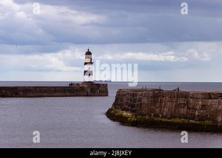 Iconic striped Seaham lighthouse on sea wall with cloud reflections ...