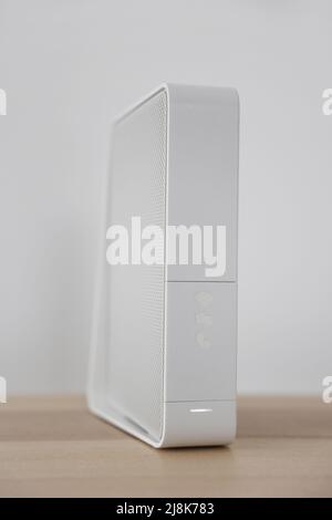 Modern white wi-fi router on table near light wall Stock Photo - Alamy