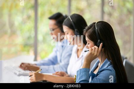 Team of diverse hotline operators with headphones providing service to ...