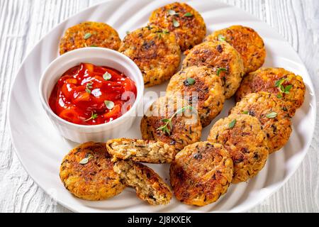 cauliflower patties on white plate with tomato sauce on white textured ...
